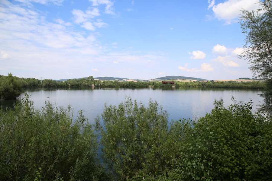 Um lago tranquilo rodeado por vegetação e colinas.