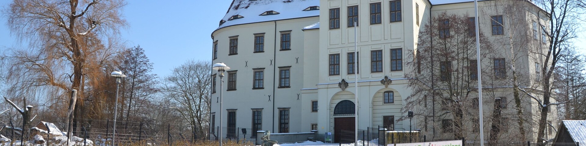 Um edifício grande e branco com várias janelas e telhado coberto de neve.
