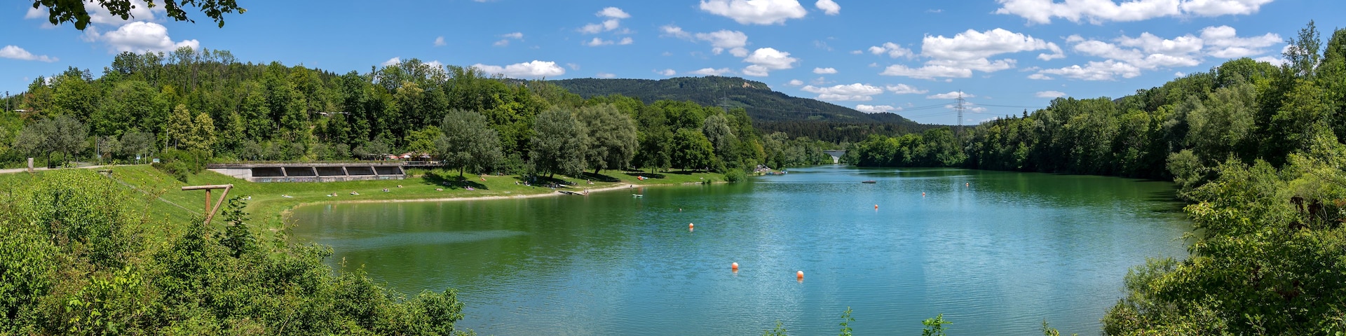 Um lago tranquilo rodeado por vegetação exuberante e colinas.