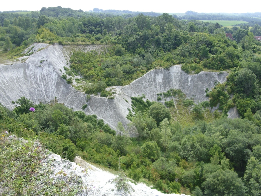 Paisagem com um penhasco grande e erodido, rodeado por vegetação densa.