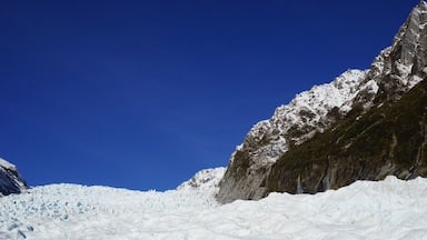 Um grupo de pessoas caminhando em uma geleira coberta de neve sob um céu azul e límpido.