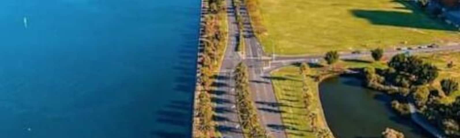Paisagem costeira com uma longa orla à beira-mar, um parque e edifícios modernos altos.