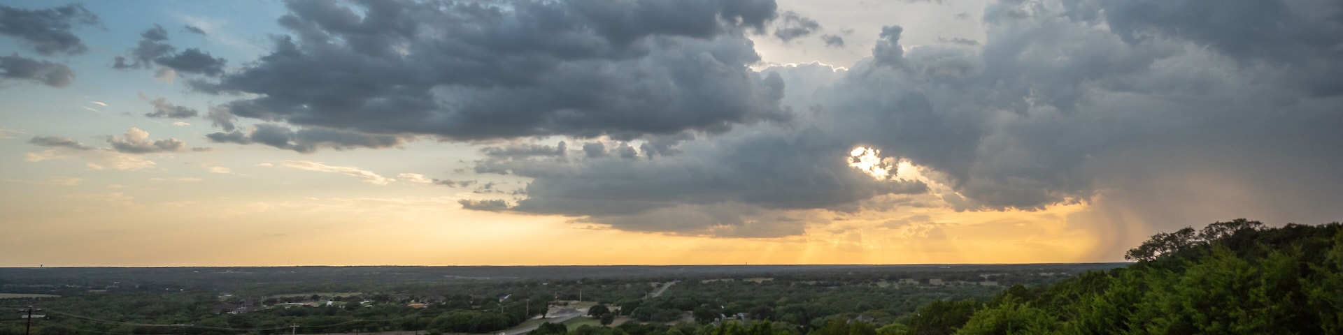 Paisagem com estrada sinuosa, vegetação densa e céu nublado.