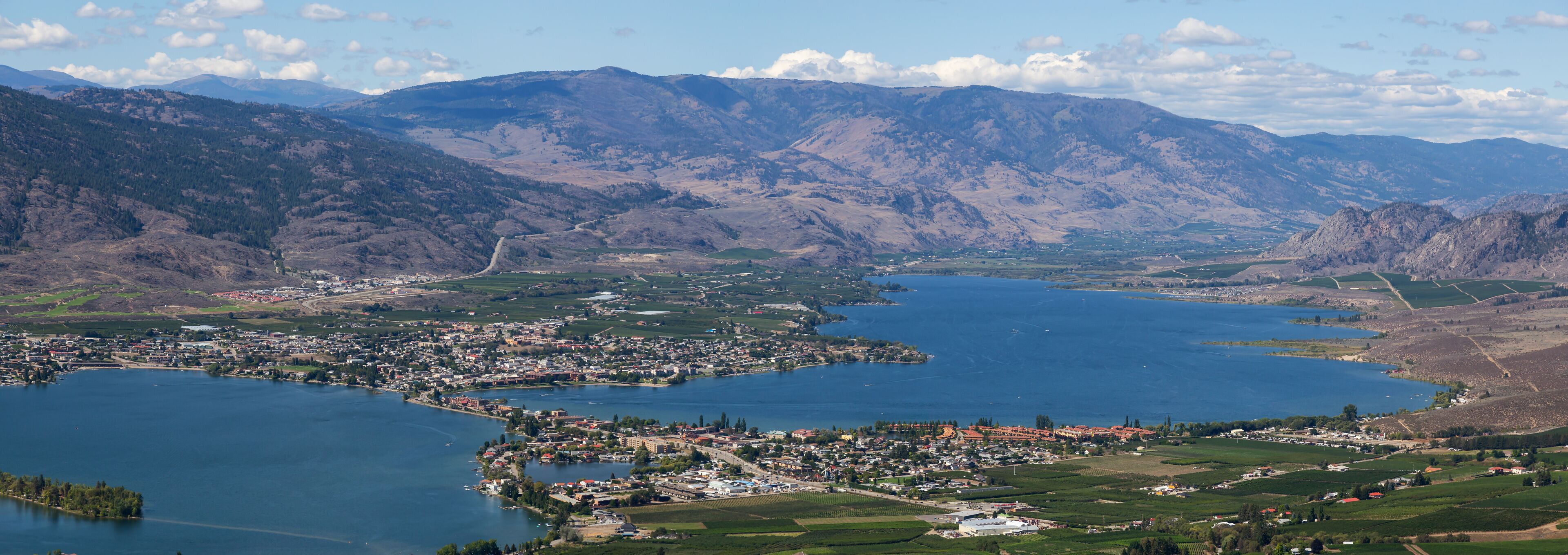 Uma cidade à beira de um grande lago, rodeada por montanhas.