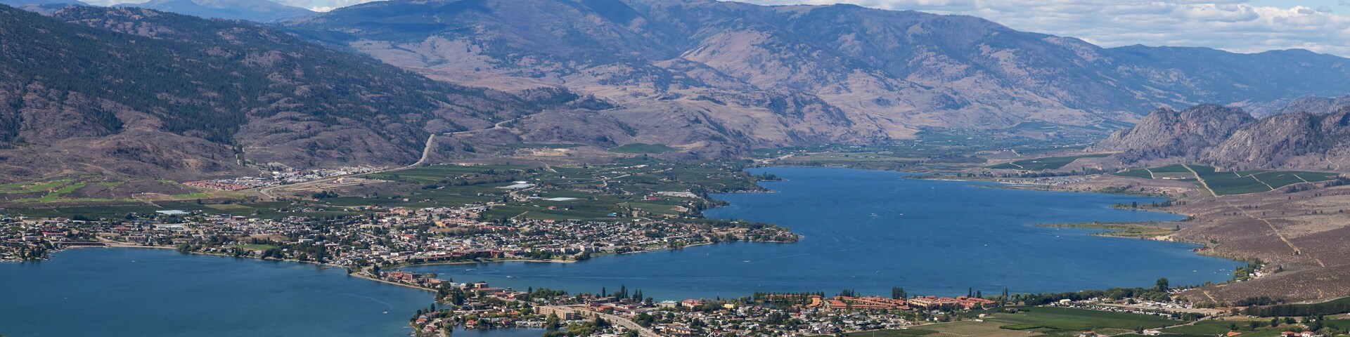 Uma cidade à beira de um grande lago, rodeada por montanhas.