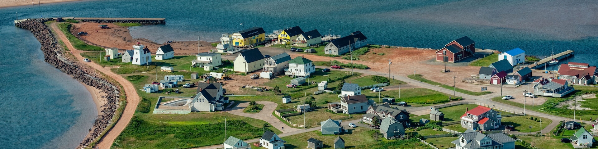 Uma vila costeira com casas, um farol e uma praia.