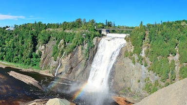 Uma grande cachoeira, um rio e um morro coberto por floresta.