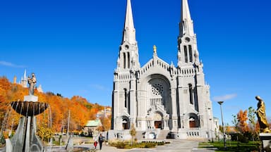 Uma catedral imponente com duas torres altas, uma rosácea central e estátuas em primeiro plano.