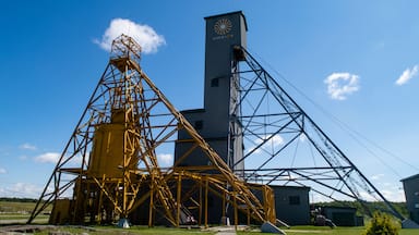 Uma grande estrutura industrial com uma torre imponente e uma grua amarela.