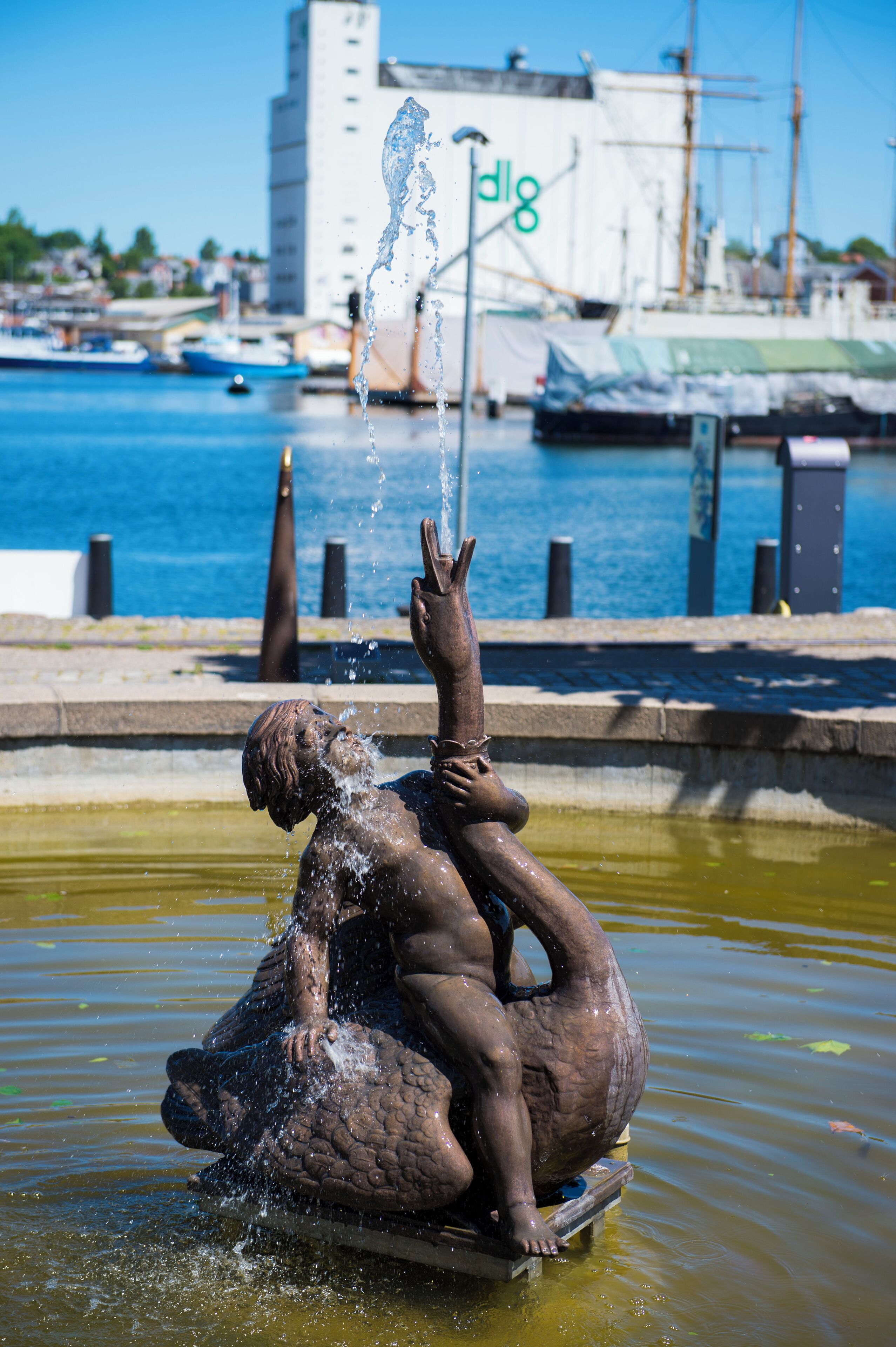 Estátua de bronze de um homem com água jorrando da mão em uma fonte.