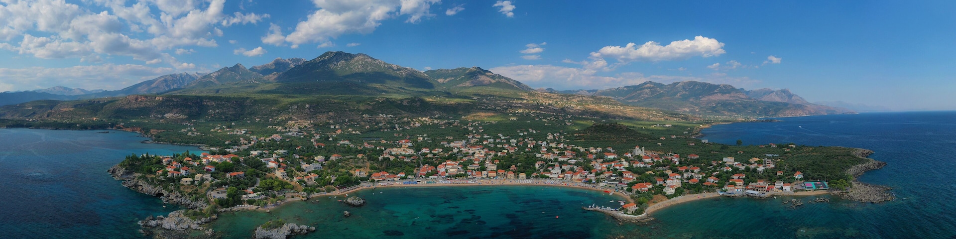 Vista aérea de uma cidade costeira com montanhas ao fundo.
