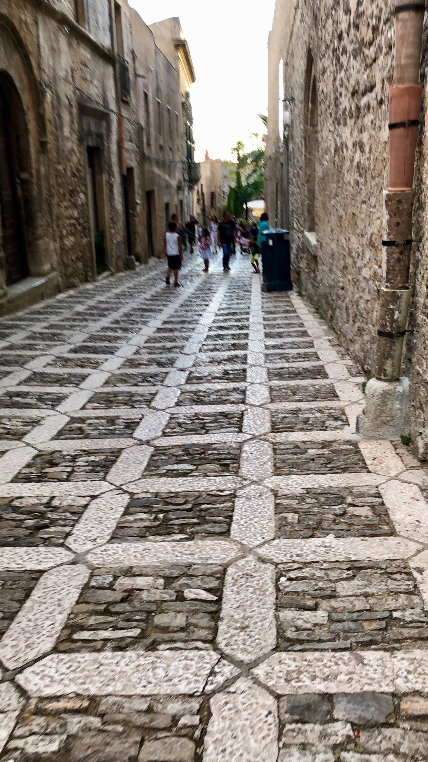 Uma rua de paralelepípedos em uma cidade antiga, com edifícios de pedra de ambos os lados.