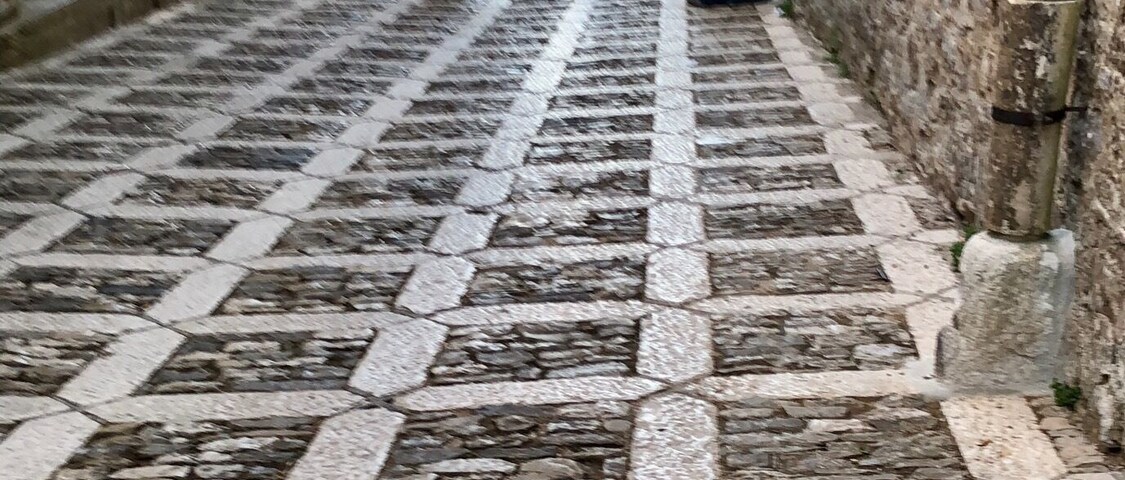 Uma rua de paralelepípedos em uma cidade antiga, com edifícios de pedra de ambos os lados.