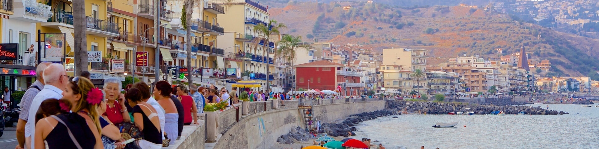 Giardini Naxos caracterizando uma cidade litorânea e uma praia assim como um grande grupo de pessoas