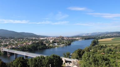 Um rio com uma ponte, uma cidade e montanhas ao fundo.