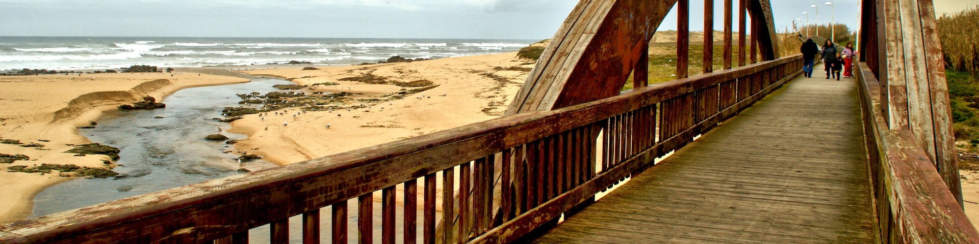 Uma ponte de madeira sobre uma praia, com ondas quebrando por perto.