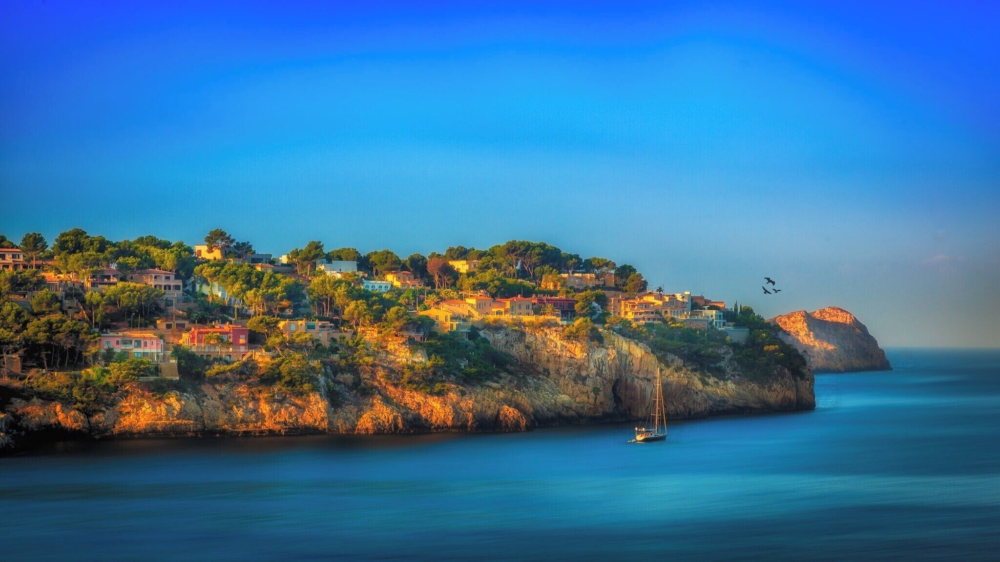 Uma vila costeira com edifícios numa encosta com vista para o mar.