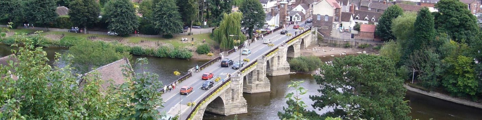 Uma ponte de pedra sobre um rio, com uma cidade ao fundo.