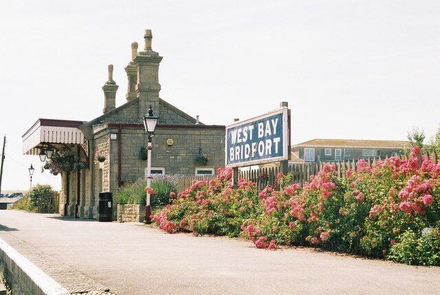 A building with a sign reading "West Bay Bridgport" and a flower garden in front.