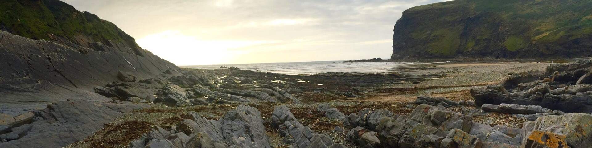 Paisagem costeira rochosa com falésias e uma praia.