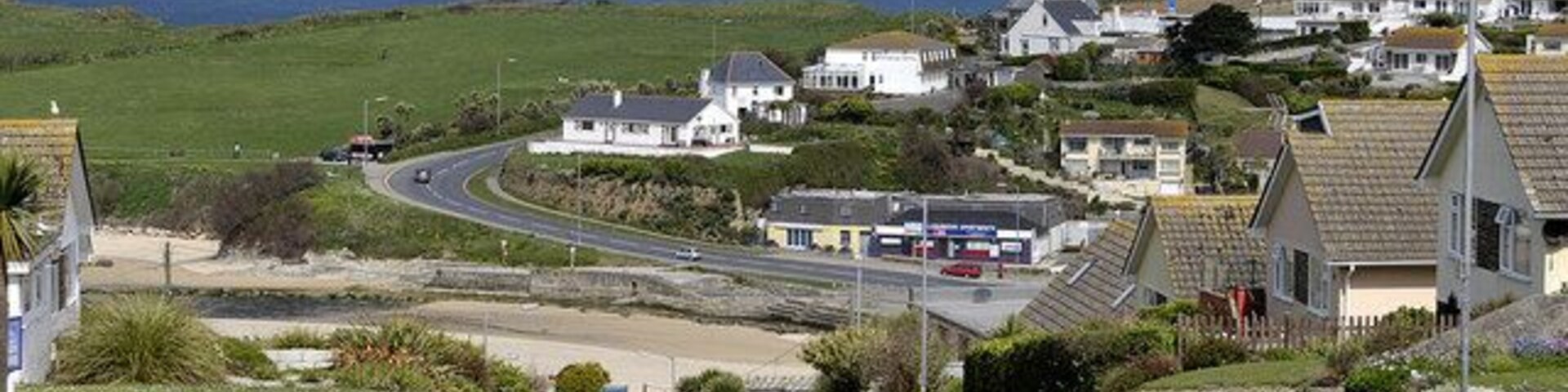Uma cidade costeira com casas, uma estrada sinuosa e o mar ao fundo.