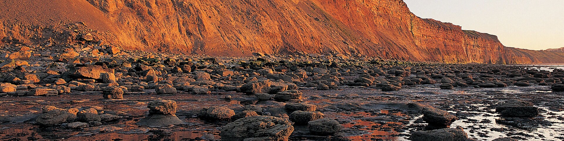 Uma costa rochosa com grandes pedras e um penhasco íngreme.