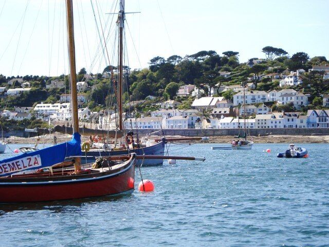 Uma vila costeira com barcos na água, casas no morro e céu claro.