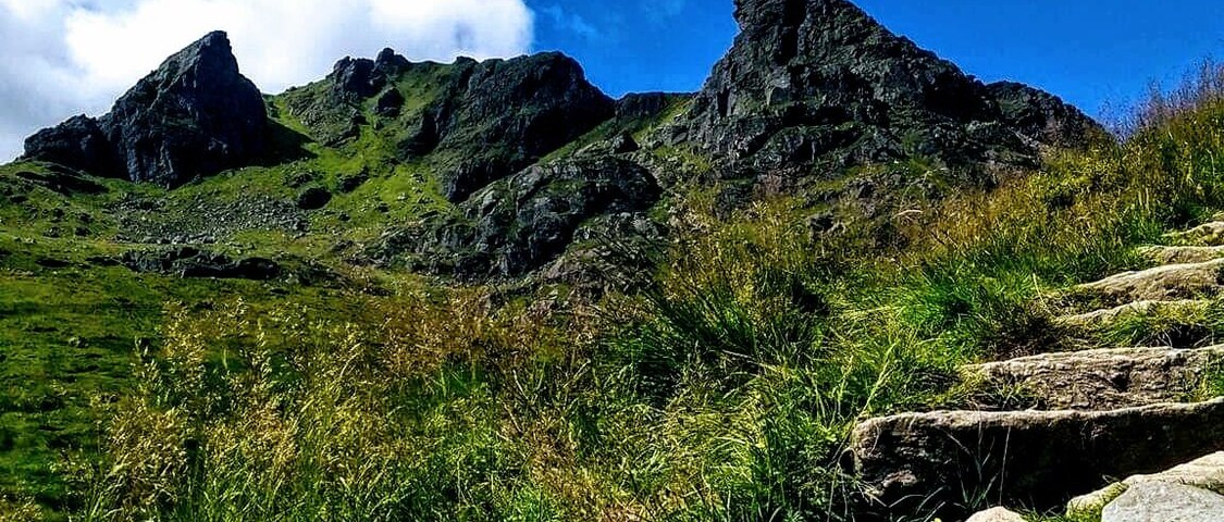 Paisagem montanhosa com terreno rochoso e áreas gramadas.