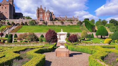 Um castelo com um jardim bem cuidado e uma estátua em primeiro plano.