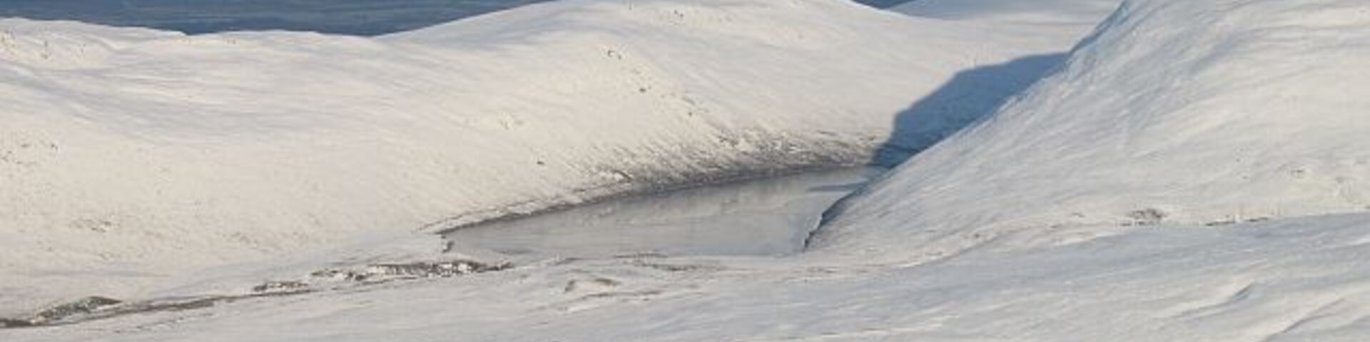 Paisagem coberta de neve com relevo ondulado e um estreito canal de neve.