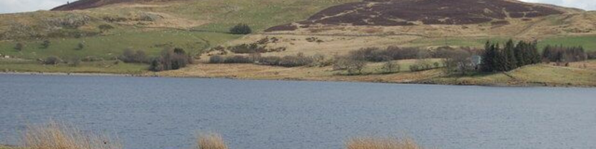 Um lago com uma colina ao fundo.