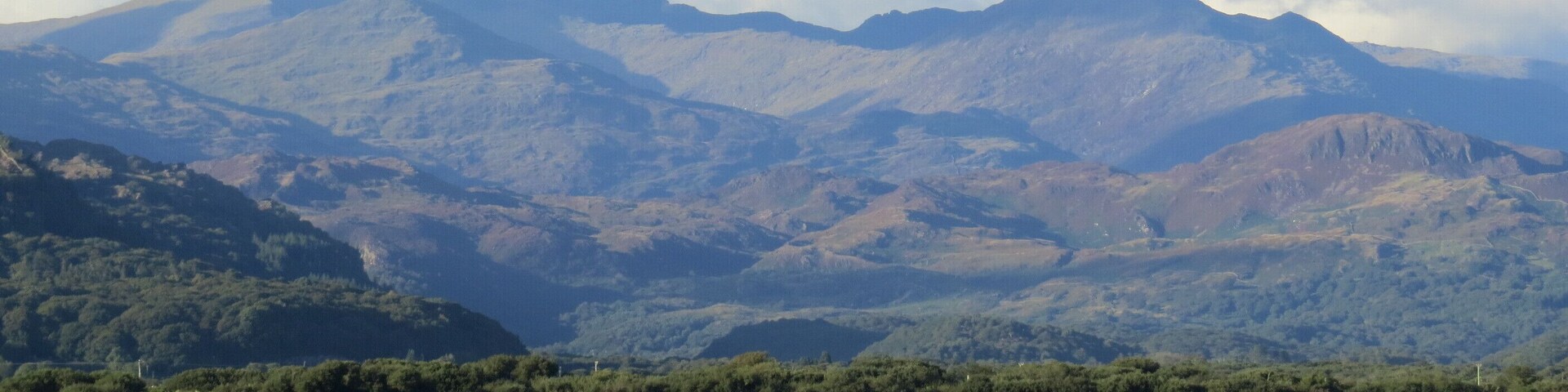 Um rio serpenteando por um vale, com montanhas ao fundo.