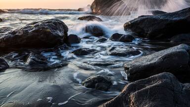 Uma costa rochosa com ondas quebrando nas pedras.