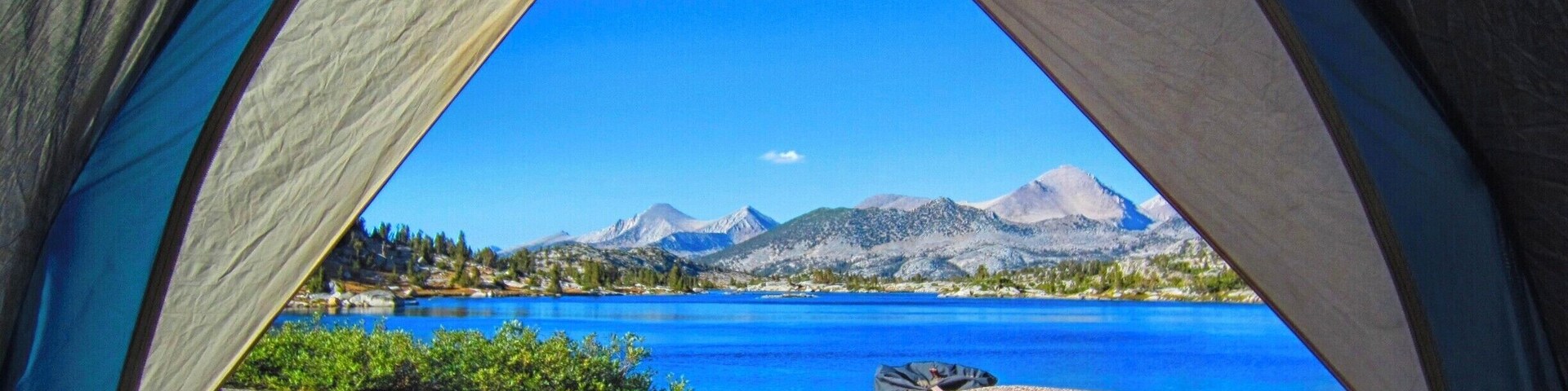 Uma tenda com vista para um lago e montanhas.