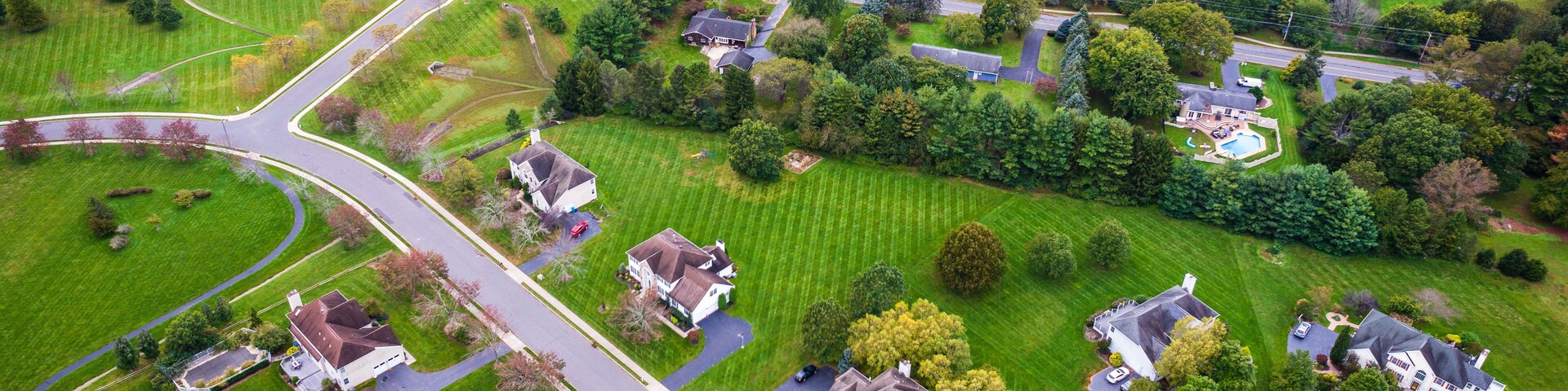 Vista aérea de um bairro residencial com casas, ruas e áreas verdes.