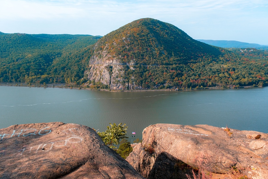 Montanha com um lago em primeiro plano e uma colina arborizada ao fundo.