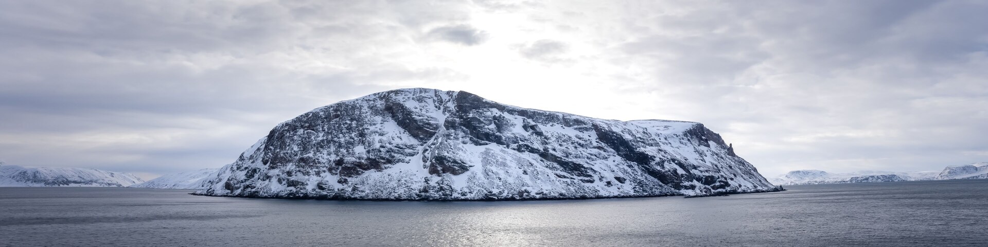 Uma montanha coberta de neve refletida em águas calmas.