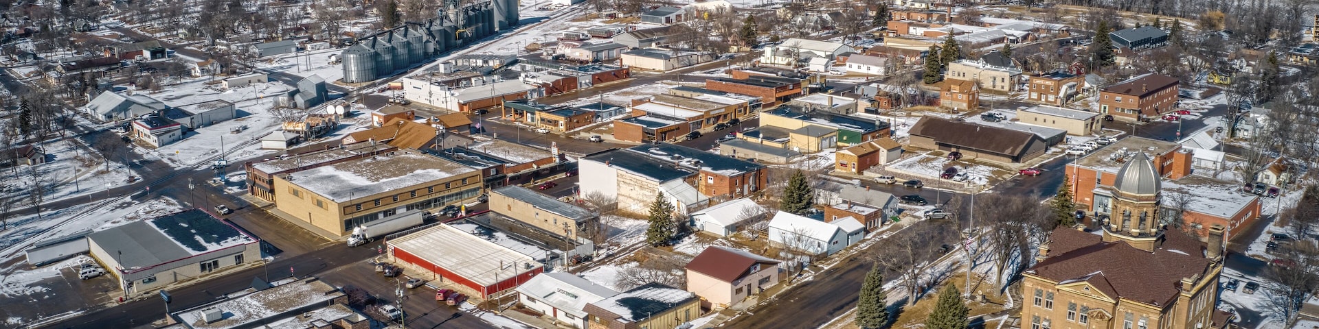 Vista aérea de uma cidade com edifícios industriais, uma igreja grande e ruas cobertas de neve.