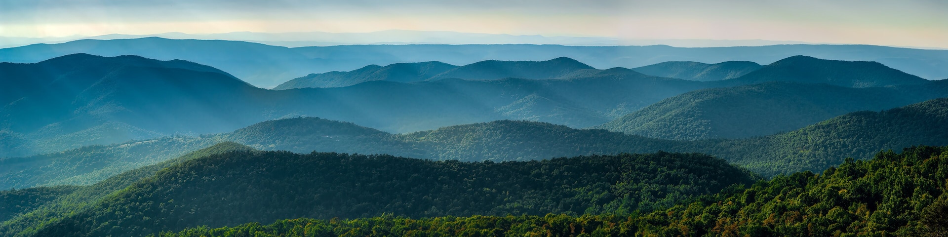 Paisagem montanhosa com florestas densas e cadeias de montanhas sobrepostas.