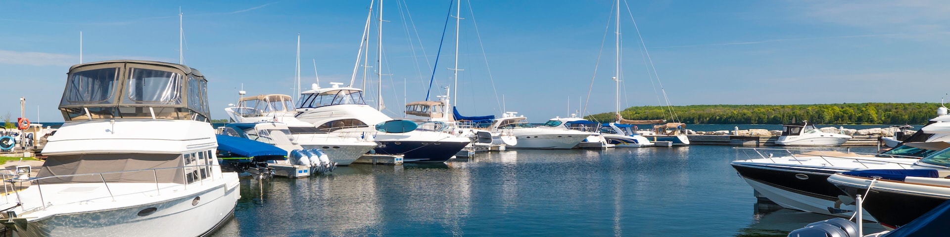 Uma marina com vários barcos atracados, águas calmas e céu azul claro.