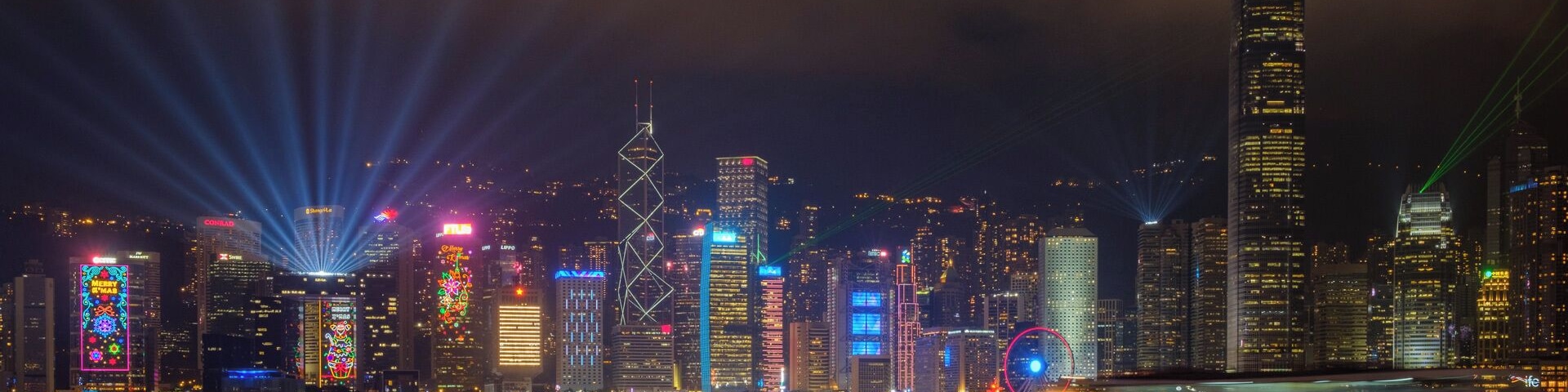 Paisagem urbana noturna com edifícios iluminados e um rio.