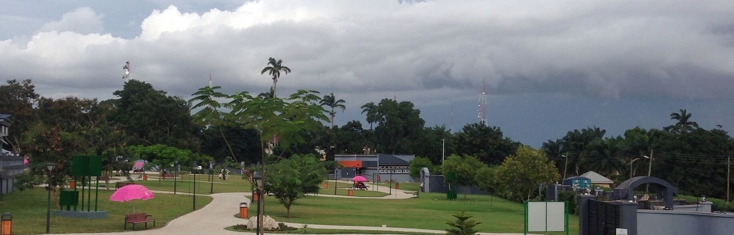 Um parque com caminhos, bancos e um céu grande e nublado.
