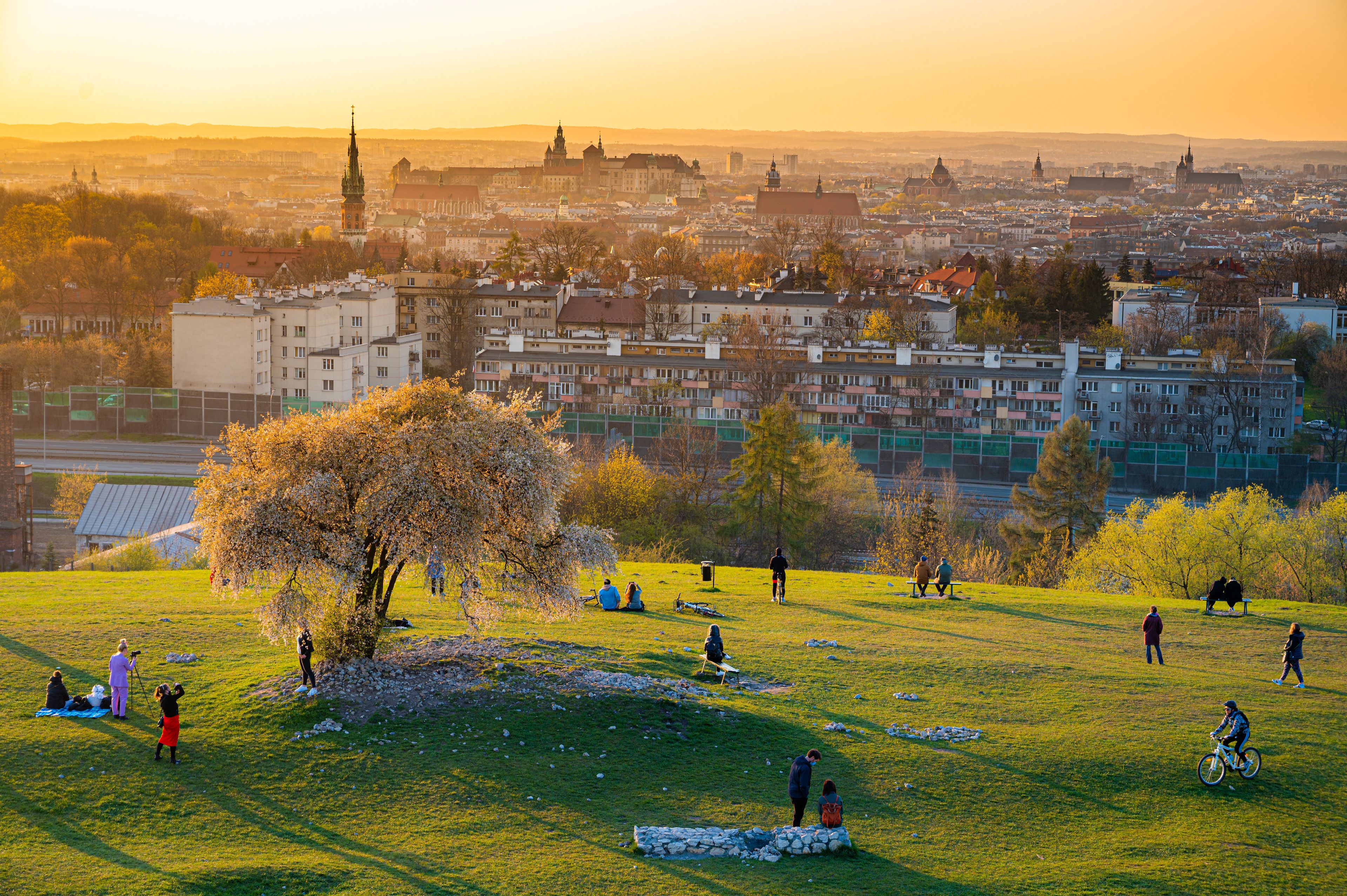 Paisagem urbana com edifícios históricos e um parque com pessoas e árvores.