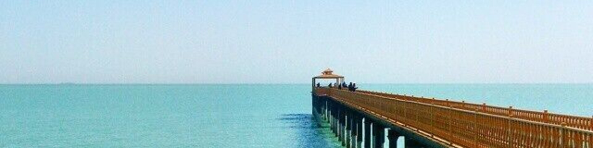 Um cais extenso que se projeta sobre um mar calmo sob um céu limpo.