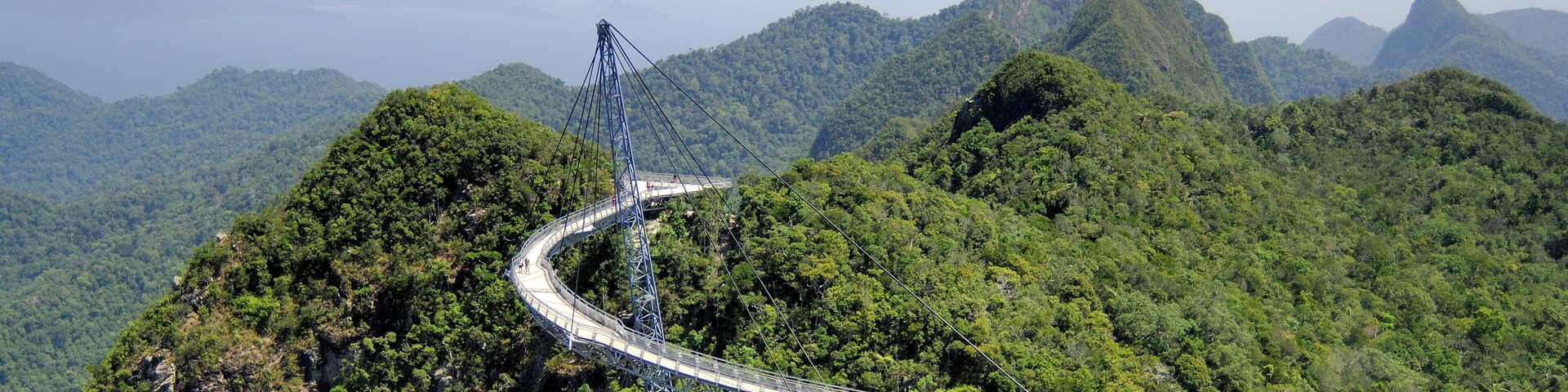 Uma ponte sinuosa sobre uma paisagem montanhosa exuberante.