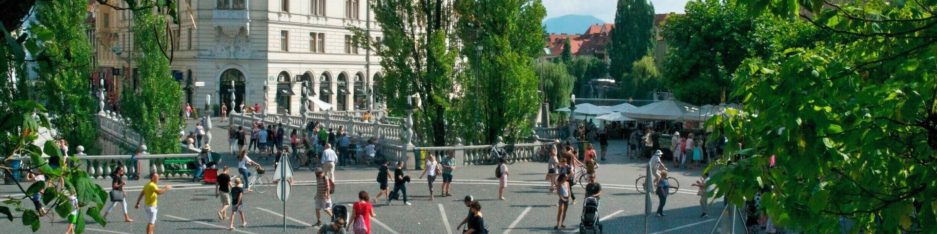 Uma praça pública com calçamento de pedra, rodeada por árvores e edifícios.