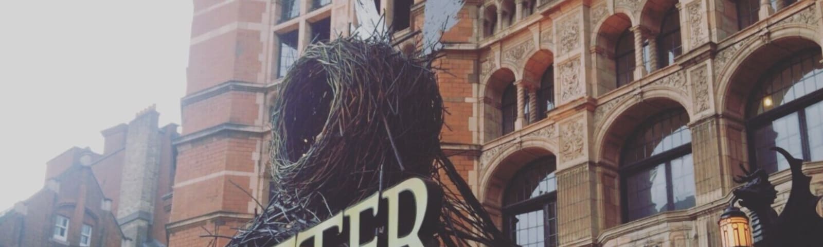 Um edifício com arquitetura elaborada e uma placa com a inscrição "Harry Potter e a Criança Amaldiçoada".