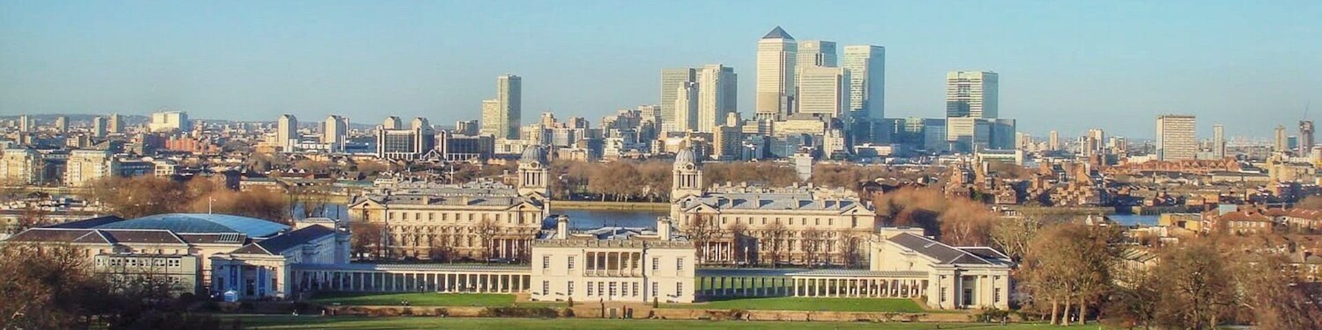 Paisagem urbana com arranha-céus modernos, edifícios históricos e um grande parque verde.
