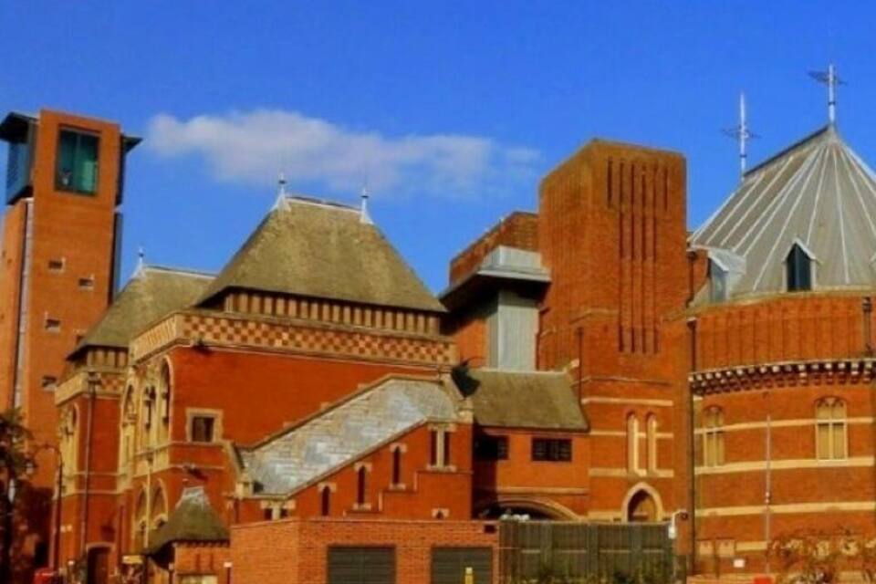 Um edifício histórico com fachada de tijolos vermelhos, uma cúpula grande e um campanário.