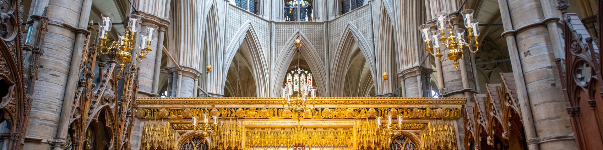 Interior de uma catedral com altares ricamente decorados, vitrais e arquitetura gótica.